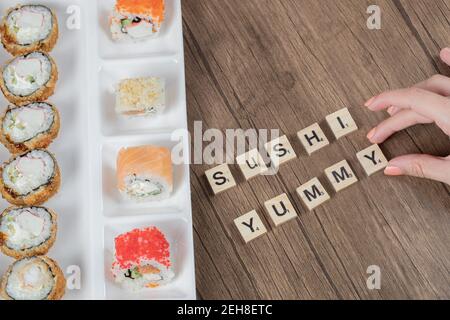 Yummy sushi writing with wooden dices around sushi rolls Stock Photo ...
