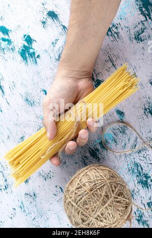 Dry spaghetti pasta and yarn on blue background Stock Photo - Alamy
