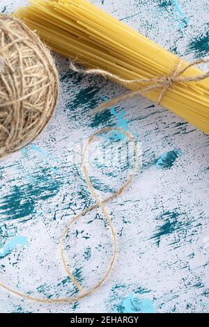 Uncooked spaghetti pasta and yarn on blue background Stock Photo - Alamy