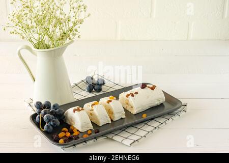 Sliced halva with nuts and dried fruits on a plate served with flowers ...