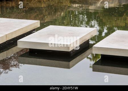 Floating stone stepping stones over a pond water feature planted with ...