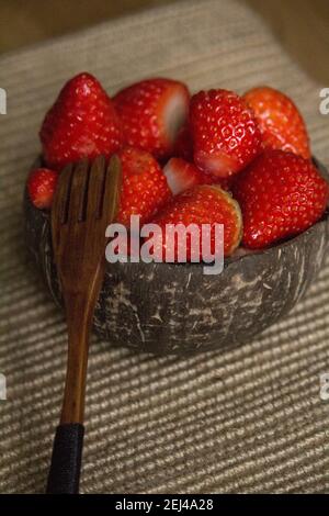 A closeup view of delicious-looking strawberries in a coconut bowl on a ...