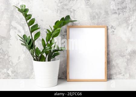 Blank poster frame and table with houseplant near blue wall Stock Photo ...