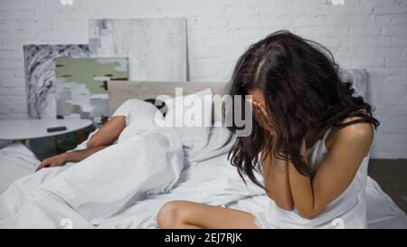 depressed woman obscuring face with hands while sitting at table served ...