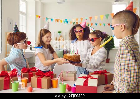 Birthday cake, party hats, gifts, balloons and confetti on red ...