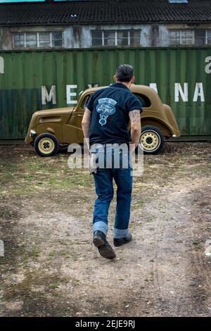 A back shot of a man walking towards a fence with a blue T-shirt and a ...