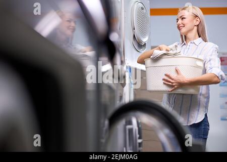 Woman getting towels form washing machine, feeling softness of linen ...