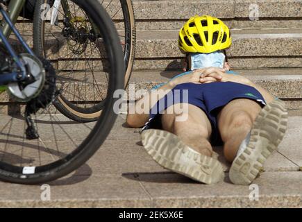 A cyclist lays on the ground while wearing a face masks as a preventive ...
