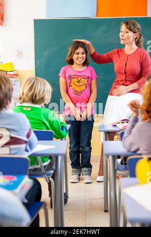 Young girl receiving praise form her teacher in a school classroom ...