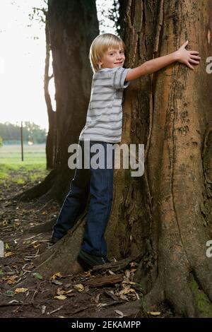 Boy hugging a tree in a garden Stock Photo - Alamy