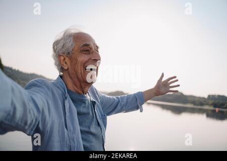 Senior man with arms outstretched standing on boat deck moored at ...