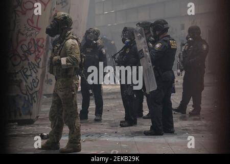 Federal officers stand out front of the federal courthouse in Portland ...