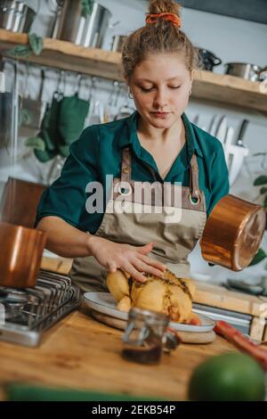Young woman cooking chicken, marinating with spices black pepper salt ...