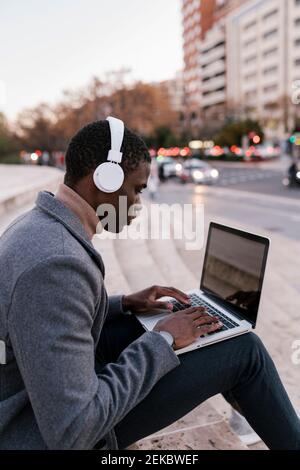 Young man wearing headphones working on his laptop at home Stock Photo ...