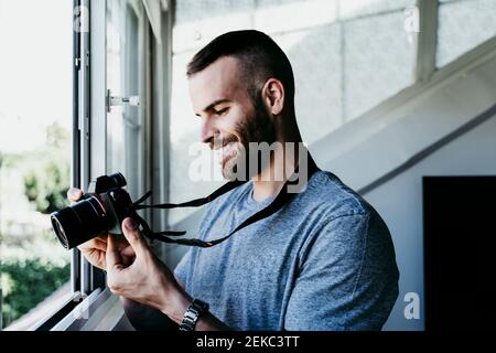 Smiling man working with camera at home Stock Photo - Alamy