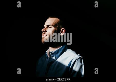 Relaxed young man standing in sunlight Stock Photo - Alamy