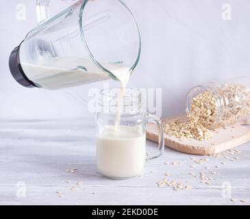 pour oat milk in glass on wood background with copy space, wide photo ...