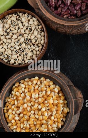 Different kinds of bean seeds, lentil, peas in dishes on a dark ...