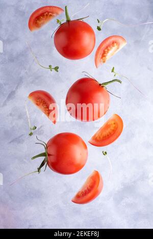 Three fresh red tomatoes with micro grins on a gray background, top ...