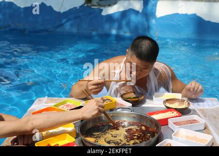 Tourists eat hotpot while sitting in a ice bucket to enjoy spicy ...