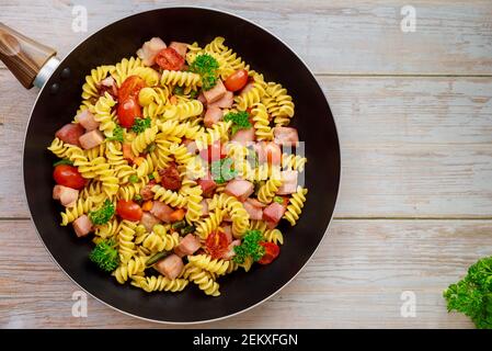 Colorful pasta rotini, cherry tomatoes and ham on pan. Close up. Top ...