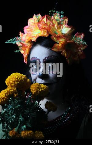 A woman disguised as Catrina poses in a field flowers on October 27 ...
