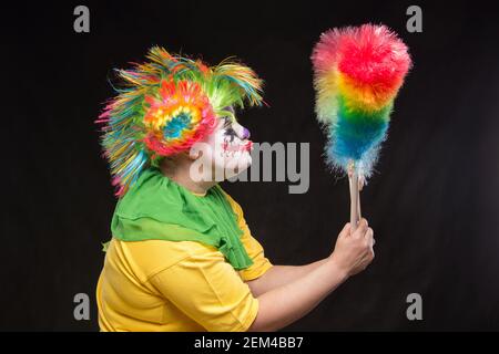 Scary clown with colorful mohawk and a smile with a lollipop on a black ...