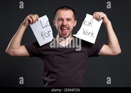 Portrait of a man tearing up an inscription on paper looking for a job ...