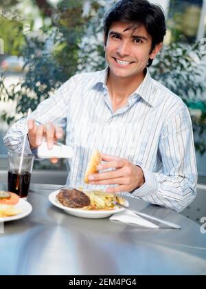 Man pouring salt on plate of food Stock Photo - Alamy