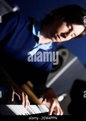 Young hispanic man playing piano at music studio recording himself ...
