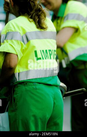 Rear view of a female street sweeper pushing a garbage can, Madrid ...