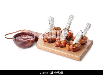 Board with tasty chicken lollipops and sauce on wooden background Stock ...
