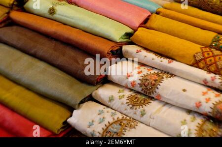 Closeup view of stacked saris or sarees in display of retail shop, for ...