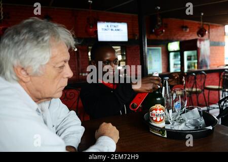 A Rwandan woman pouring Mützig beer into a glass in a pub in Kigali ...