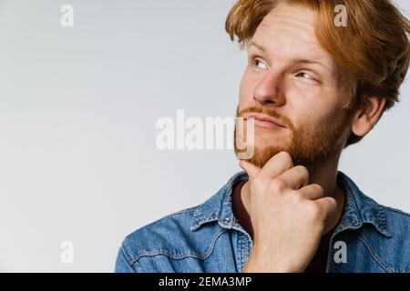 Thinking handsome ginger guy posing and looking upward isolated over ...