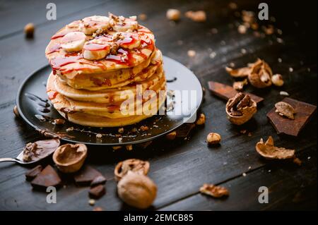 Pancake with chocolate and nut paste, walnuts and banana on a black ...