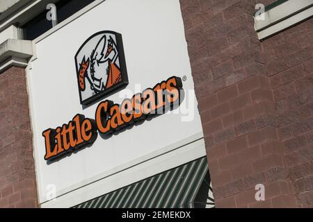 A logo sign outside of a Little Caesars restaurant location in ...