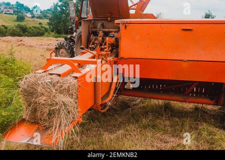 The process of harvesting hay for cattle, a tractor making bales in the ...