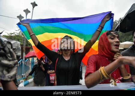 LGBTQ community member celebrates while holding a rainbow coloured flag ...