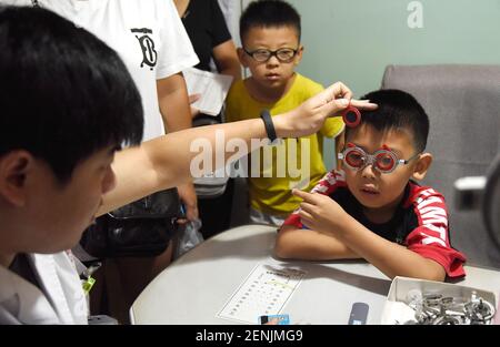 A Chinese doctor examines the eyesight of a young myopic kid at an ...
