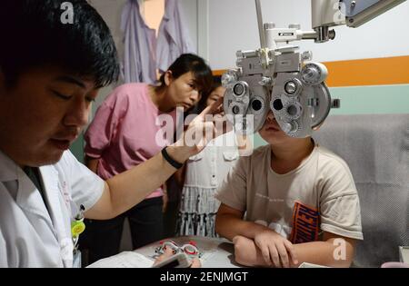 A Chinese doctor examines the eyesight of a young myopic kid at an ...