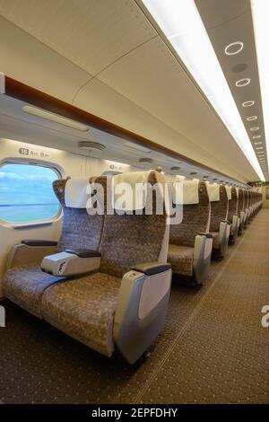 Interior of Japanese bullet train Hikari. Passengers seat in half-empty ...
