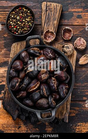 Roasted chestnuts served in a pan on a wooden cutting board. Wooden ...