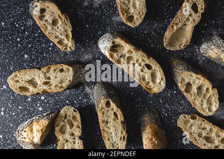 From above of appetizing crusty bread near wheat spikes and dark fabric ...