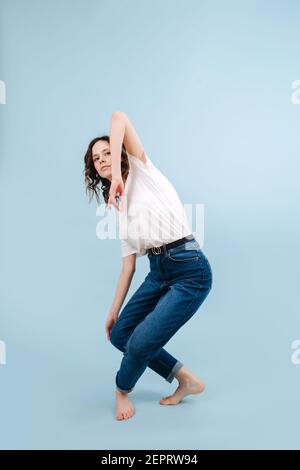 Artistic contemporary dancer poses in front of blue studio background ...