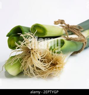Cut leeks tied with string, on a white background Stock Photo - Alamy