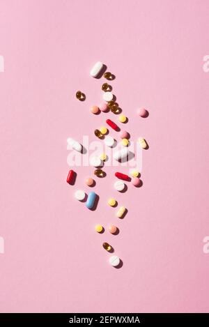 multicolored pills and capsules on a pink background Stock Photo - Alamy