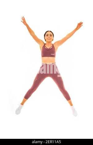 Young woman doing star jumps on the coast at sunset Stock Photo - Alamy