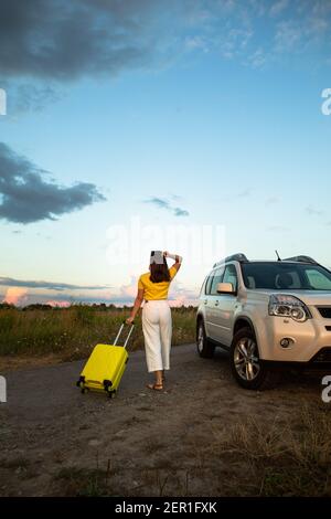 woman with luggage near white suv car plane in the air. copy space ...