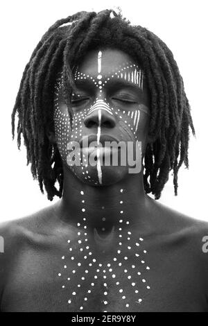 A face painted Native American shaman with half black spotted face and ...